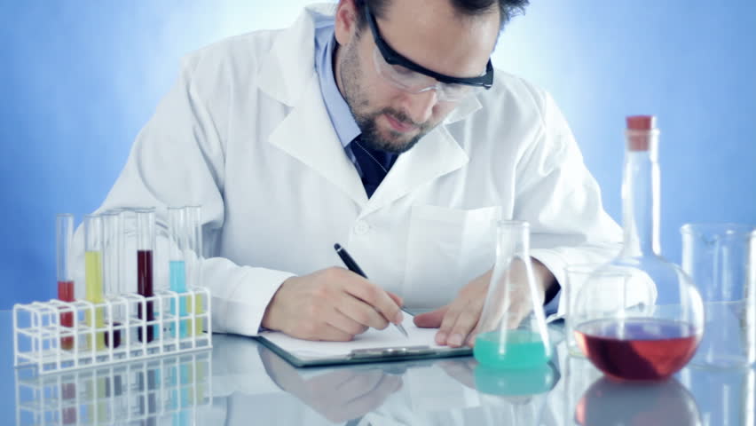 Male Scientist Mixing Chemicals In Erlenmeyer Flask And Write Results ...