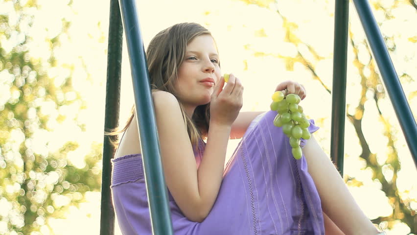 Videoclip de Smiling preteen girl eating green grapes | Shutterstock