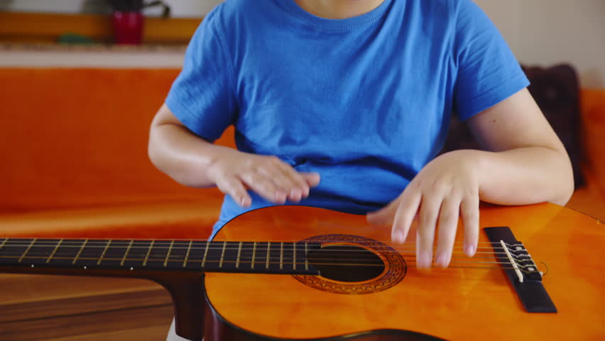 Kid Playing Guitar In Lap 4K. Big Acoustic Guitar Laying On Child Legs ...