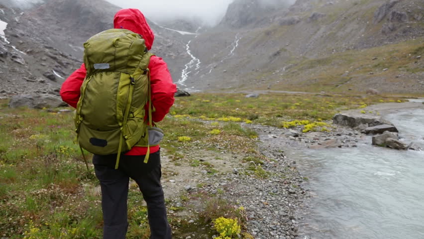 Hiker Woman In Rain Hiking Along Stream Of Water. Girl On Hike On Rainy ...