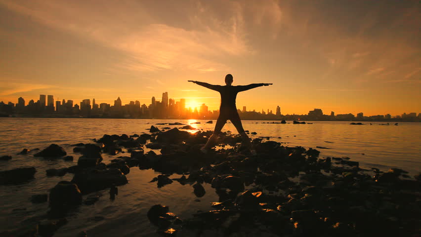 Female Practicing Yoga Exercises At Sunrise With A City Skyline ...