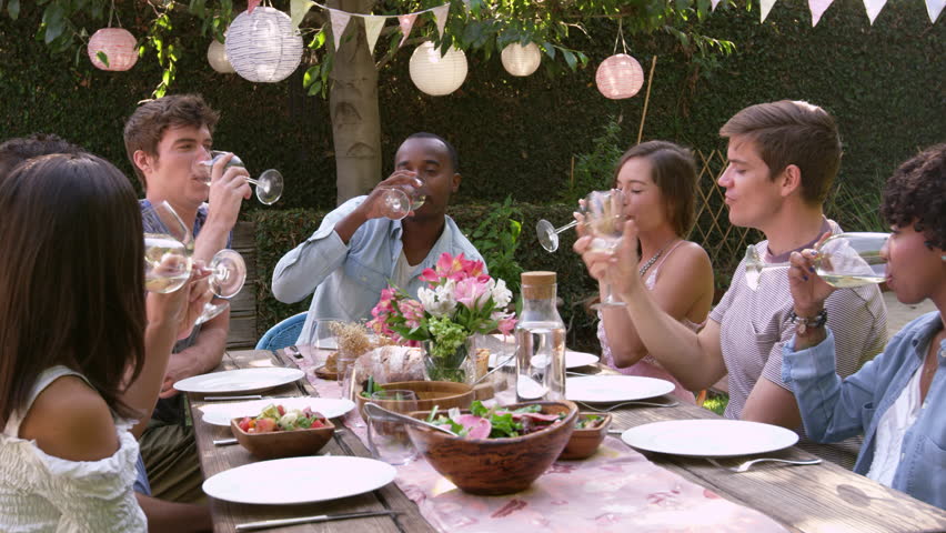 Group Of Friends Laughing And Eating At Outdoor Dinner Party In The ...