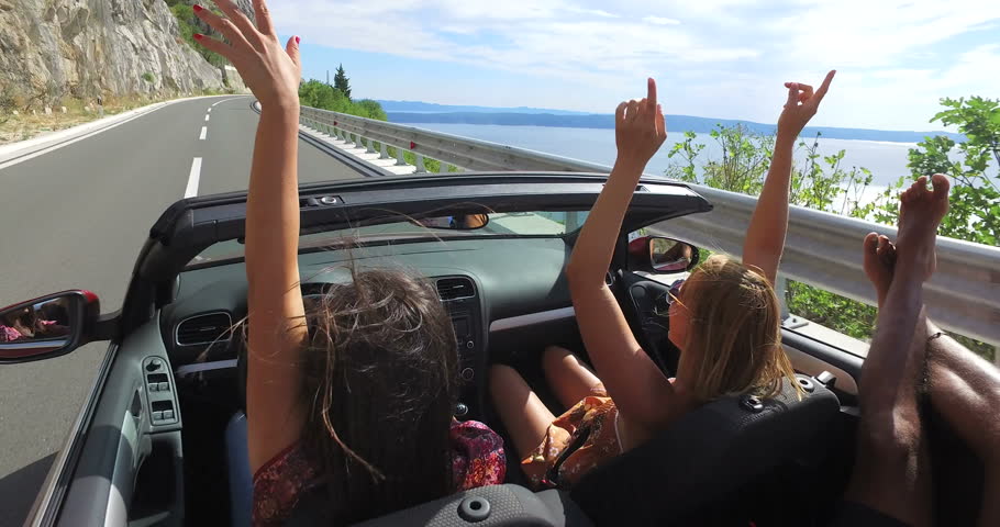Back View Of Four Young Friends Having Fun Driving On The Road Along ...
