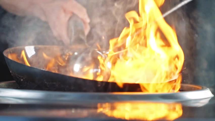 Close Up Of A Frying Pan Shooting Out Red Flames As A Chef Sautes Food ...