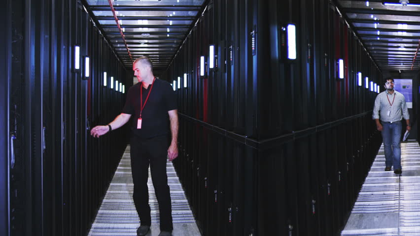 People Working In Computer Server Room Data Center. Walking Along Rows ...
