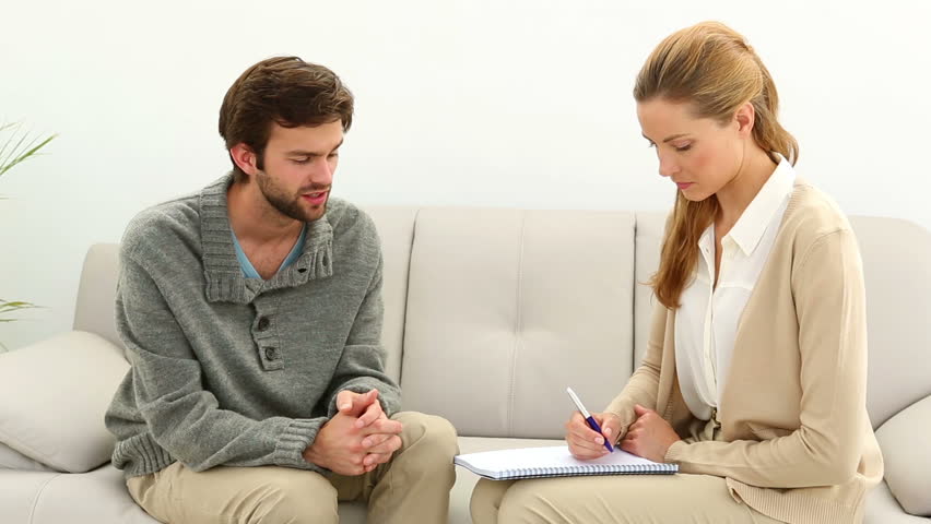 Young Man Sitting On Sofa Talking To His Therapist At Therapy Session ...